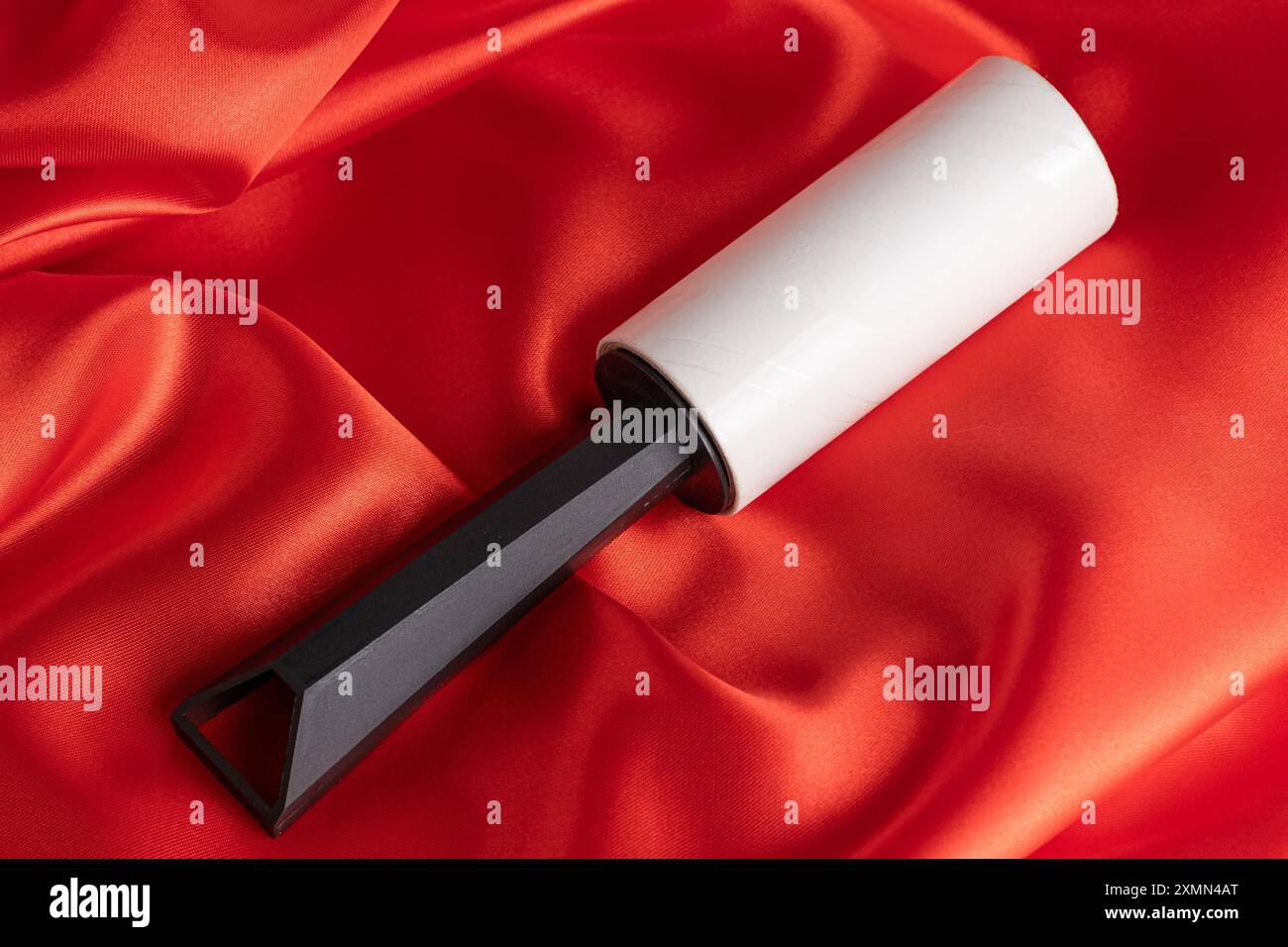 Roller for cleaning clothes on background red satin fabric Stock Photo ...