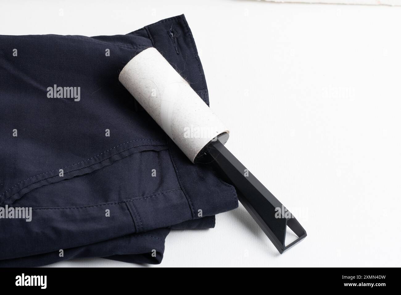 Roller for cleaning clothes with dark clean trousers on white ...