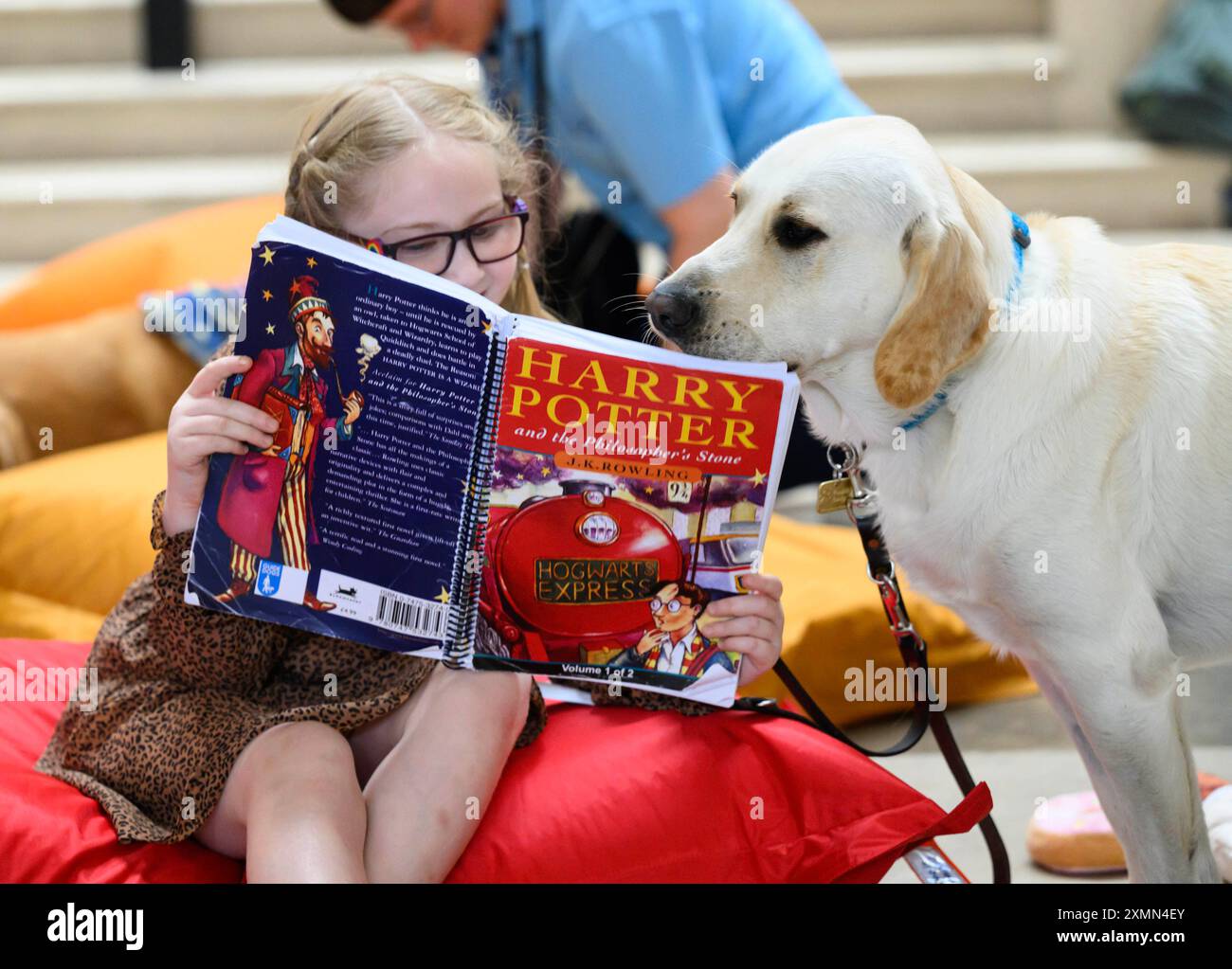 EDITORIAL USE ONLY Anya, aged eight, reads to Labrador-golden retriever ...