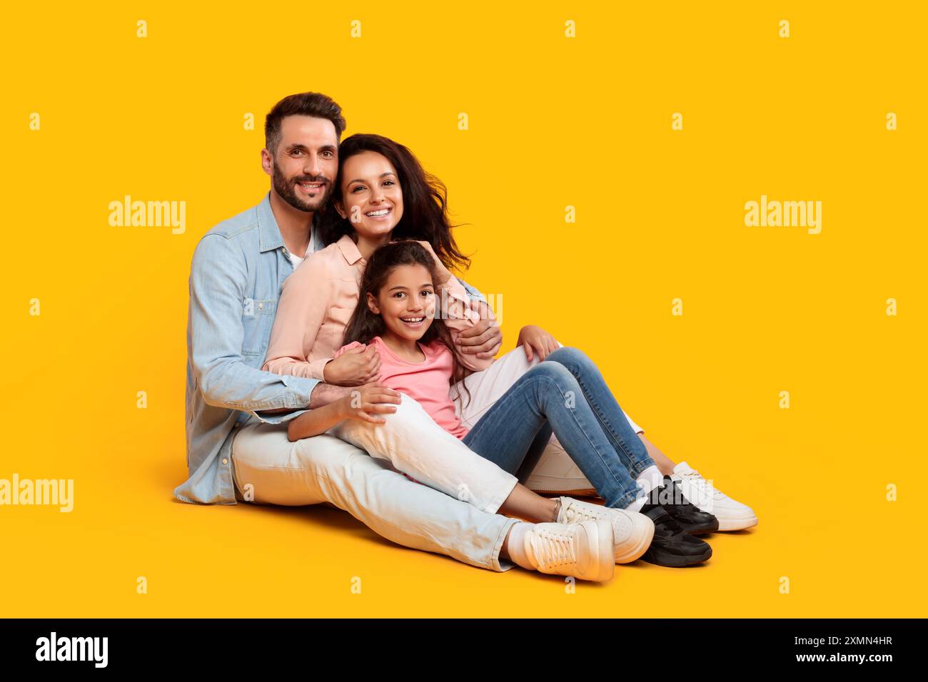 Happy Family of Three Sitting on Yellow Background Stock Photo - Alamy