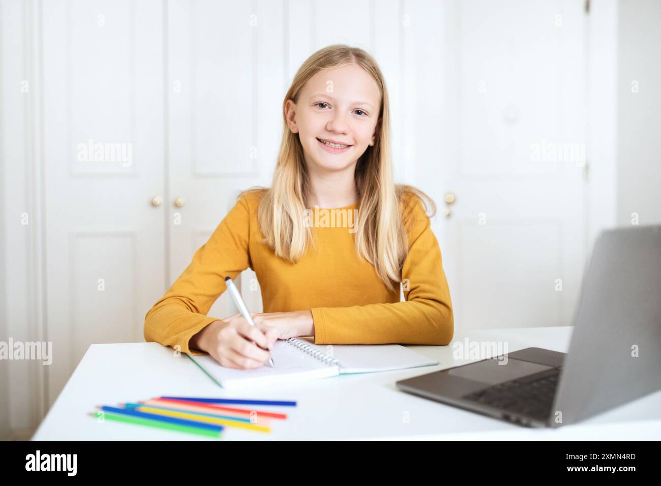 Teen Girl Smiling While Writing in Notebook at Desk Stock Photo - Alamy
