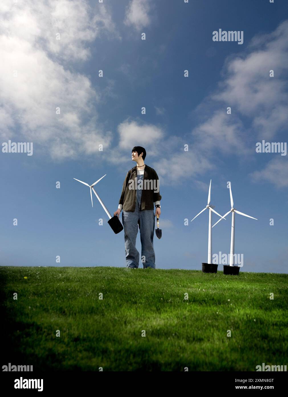 Young woman on a hill planting wind turbines Stock Photo - Alamy