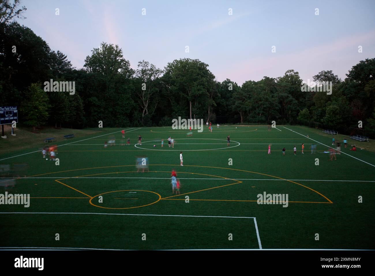 People run and play on an athletic field, some of their actions blurred ...