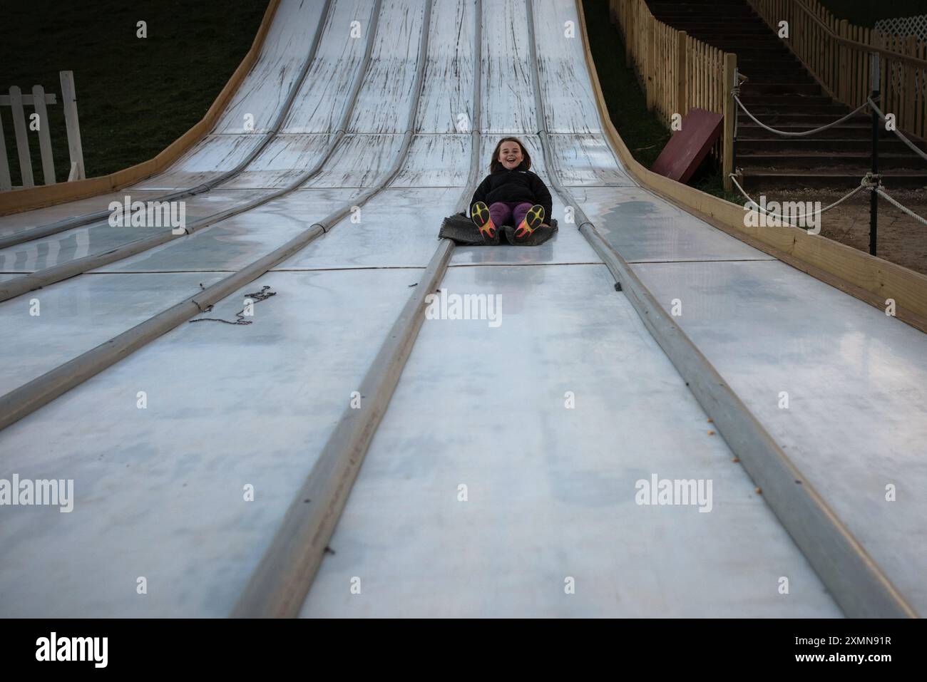 Happy young girl riding down giant slide Stock Photo - Alamy