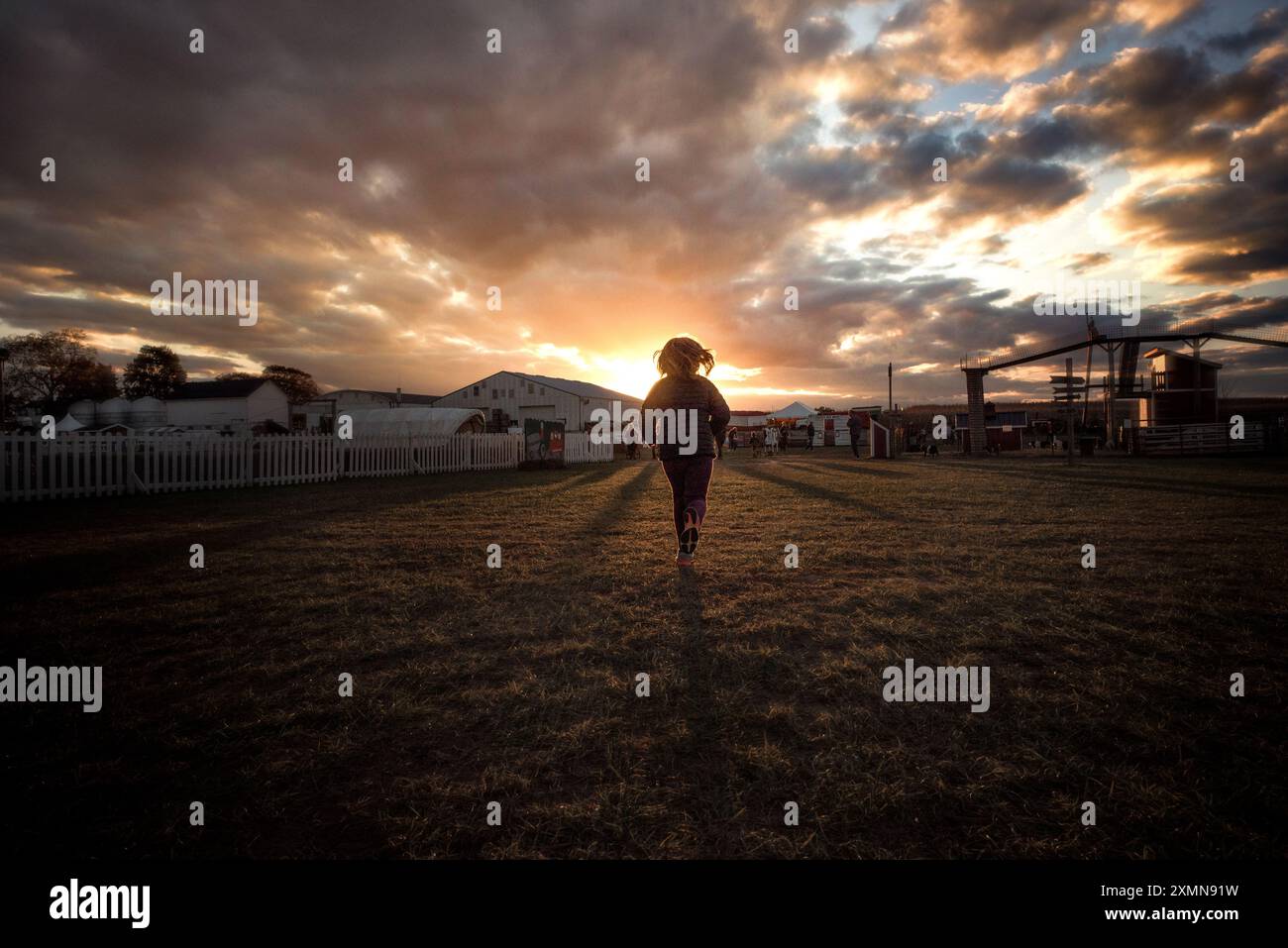Young girl running towards sunset under dramatic sky Stock Photo - Alamy