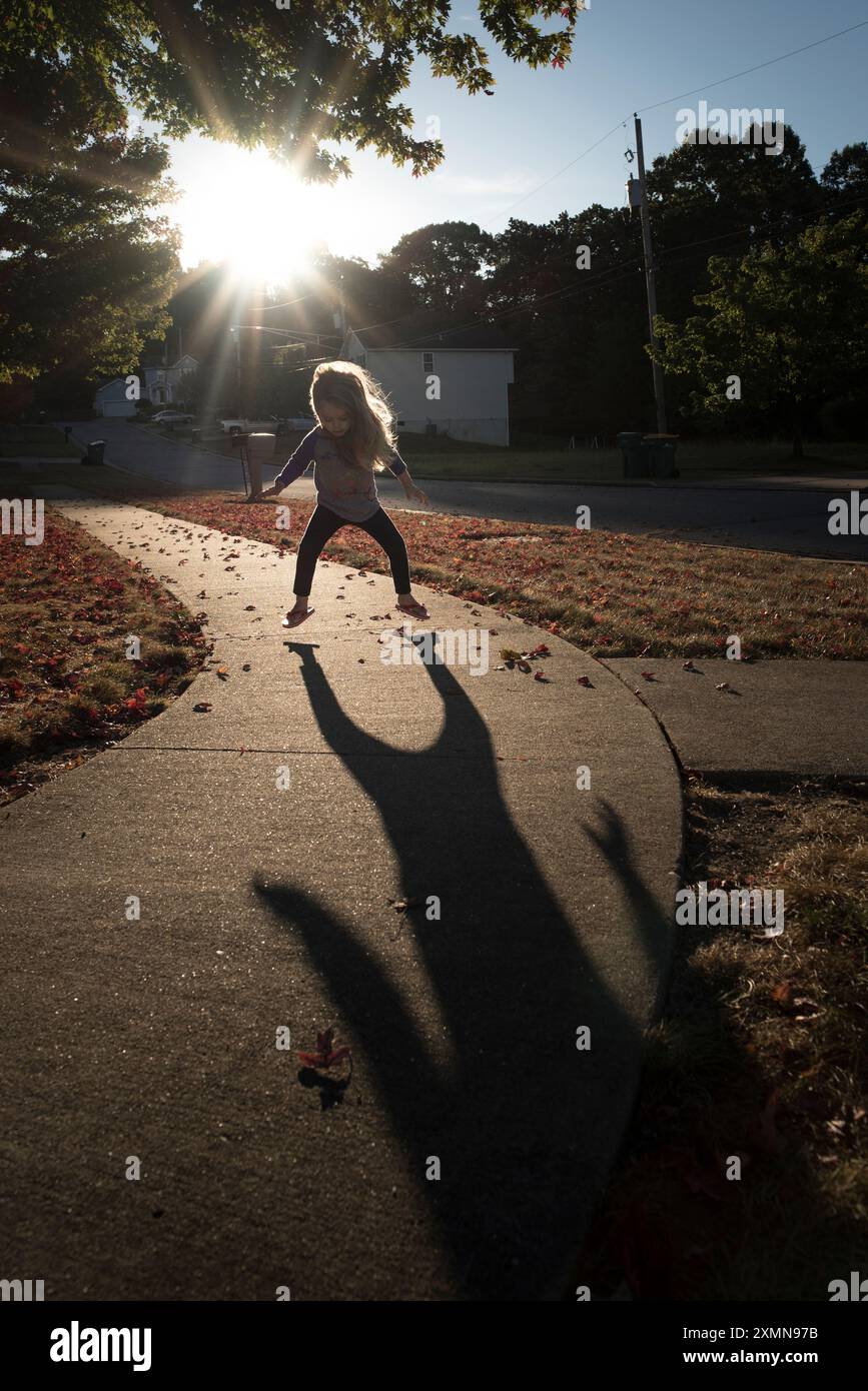 Young girl playing with shadow outdoors on sunny fall day Stock Photo ...