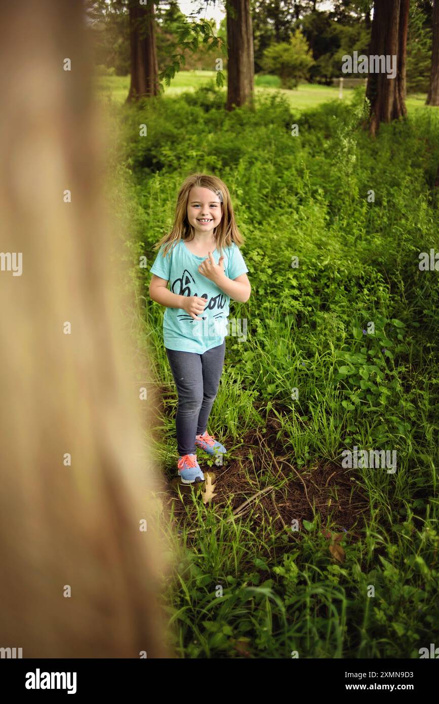 Happy little girl hiding behind tree in forest Stock Photo - Alamy