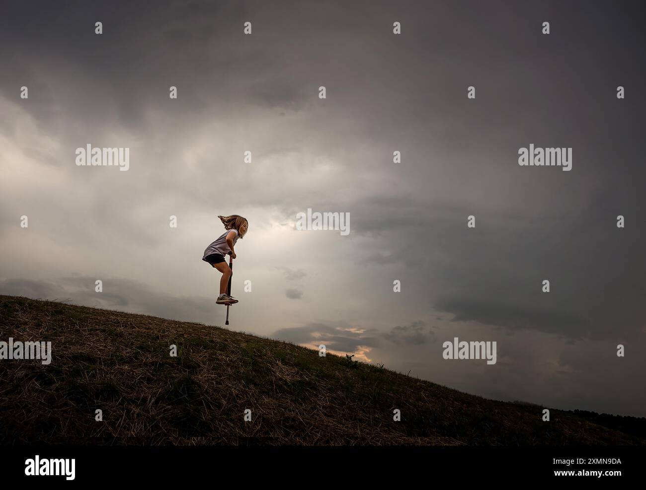 Young girl hopping down hill on pogo stick Stock Photo - Alamy