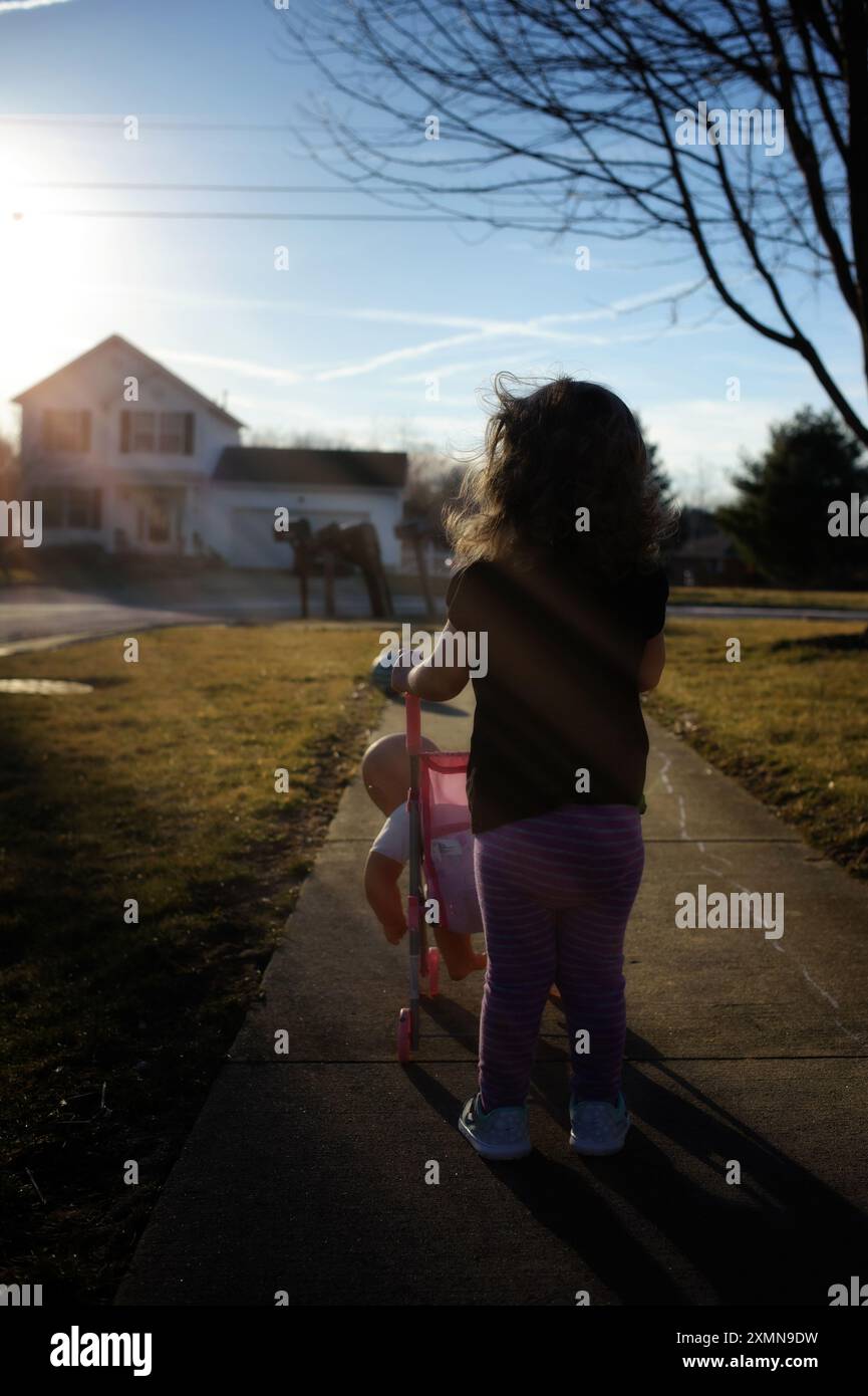 Back view of young girl pushing doll in stroller Stock Photo - Alamy