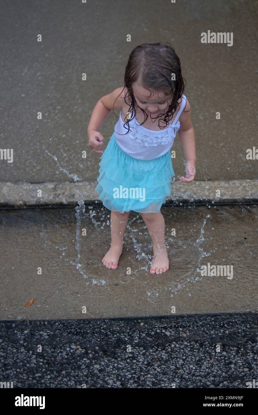 Young girl splashing in puddle during rain storm Stock Photo - Alamy
