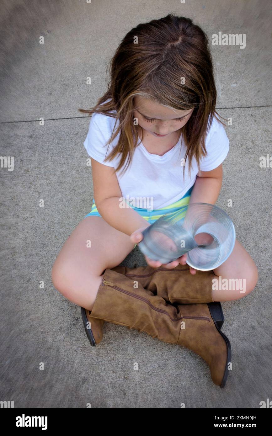 Young girl playing with slinky toy outdoors Stock Photo - Alamy