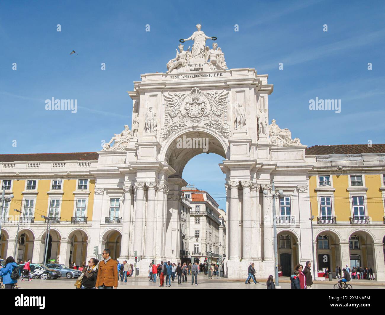 Historic arch in a European square with people walking on a sunny day ...