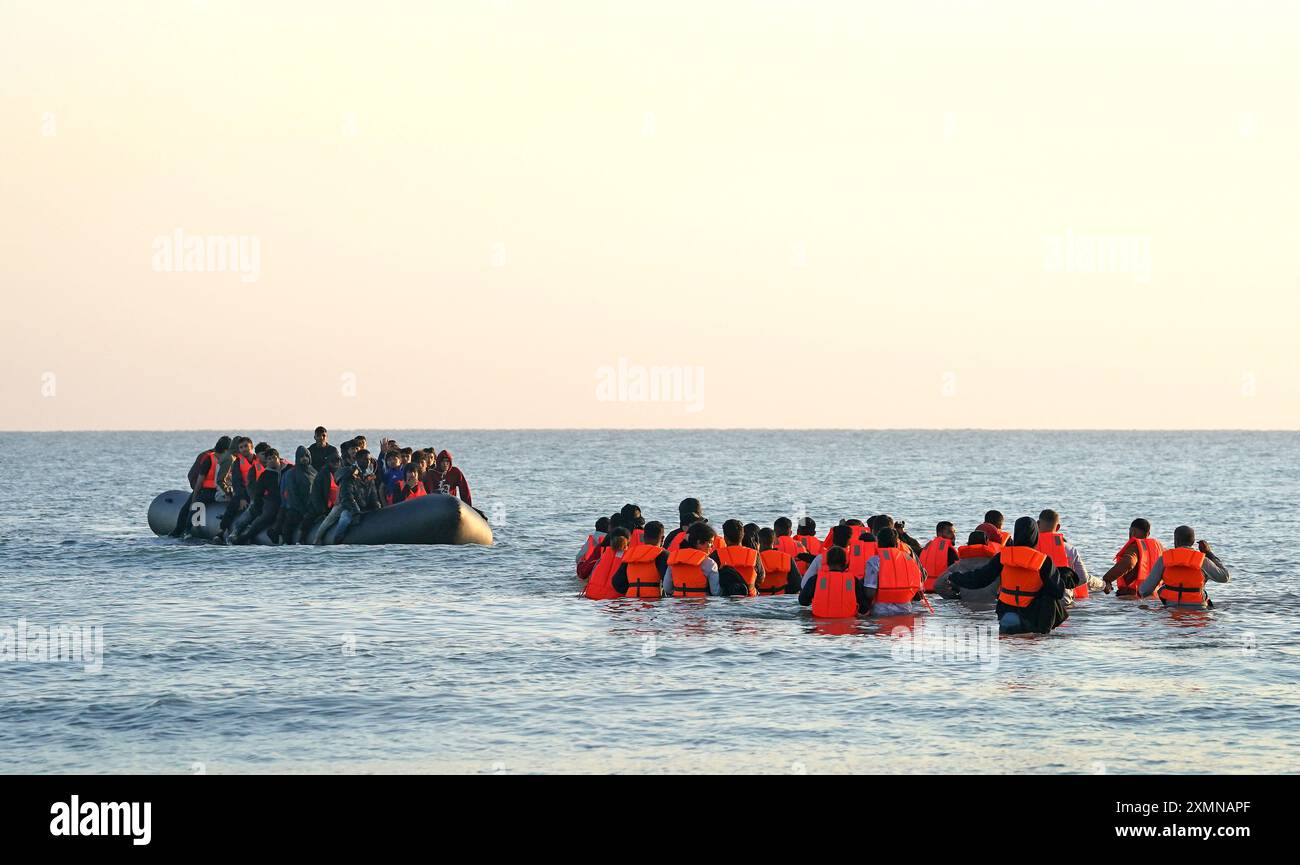 A group of people thought to be migrants wade through the sea to ...