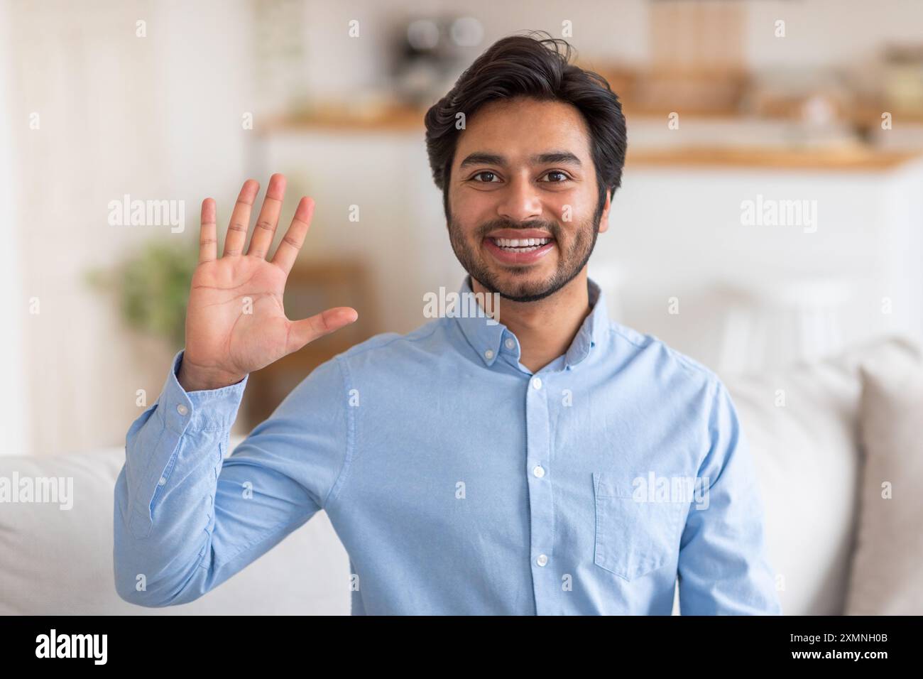 Smiling Man Waving Hello in a Home Setting Stock Photo - Alamy