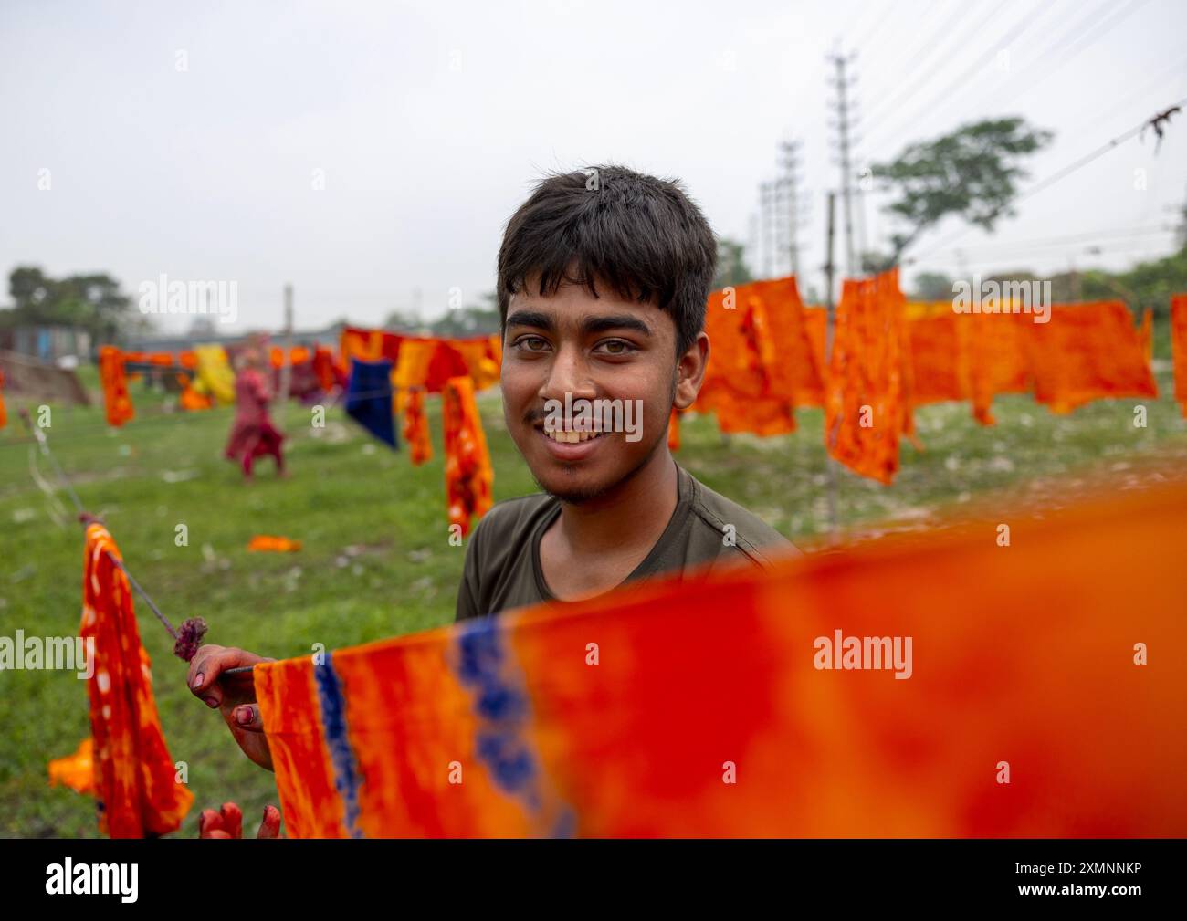 Bangladeshi smiling worker drying orange fabrics under the sun, Dhaka ...