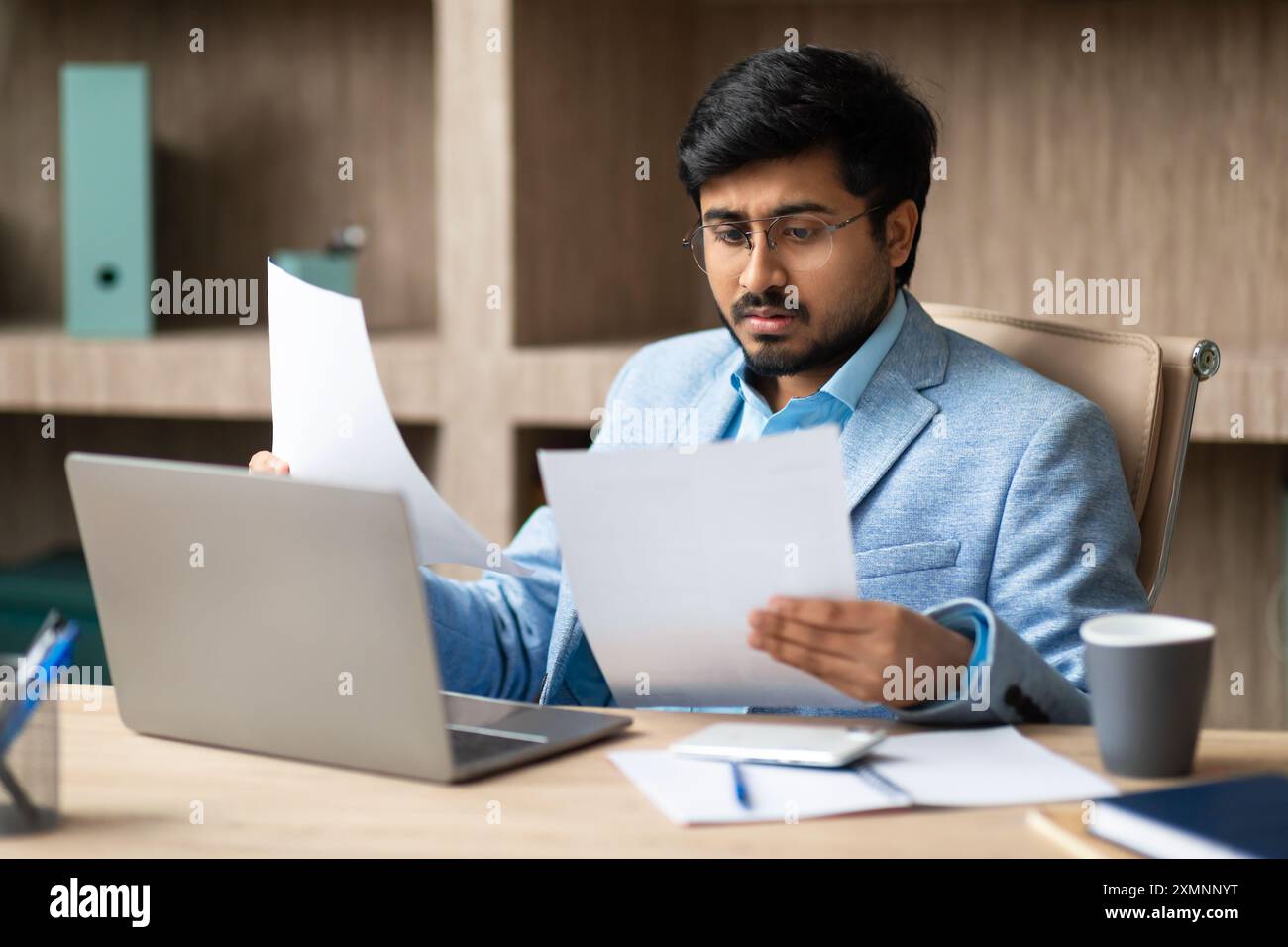 Focused Businessman Reviewing Documents at Desk With Laptop Stock Photo ...