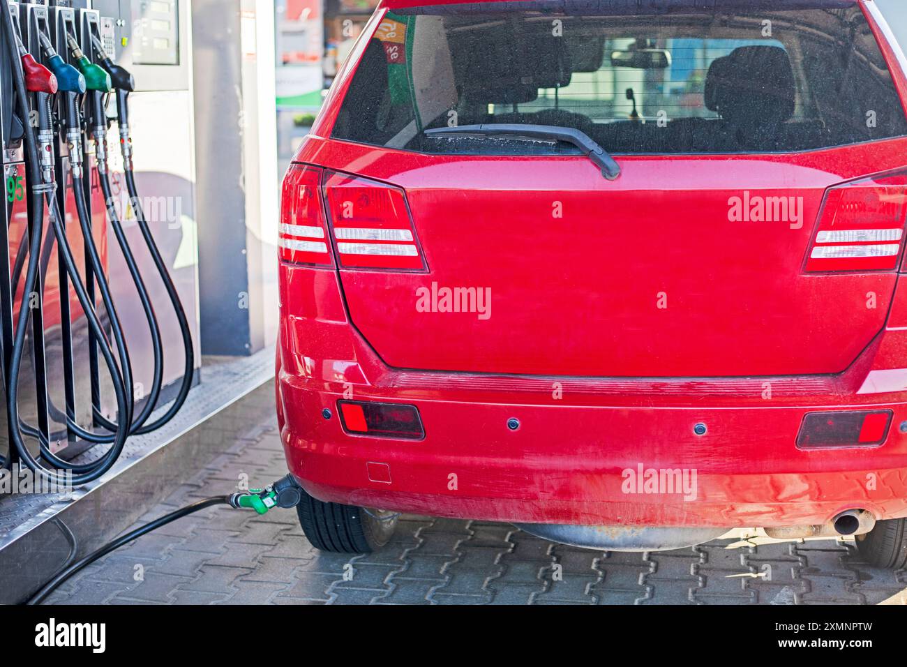 filling up a red car with LPG at a universal gas station. Economic ...