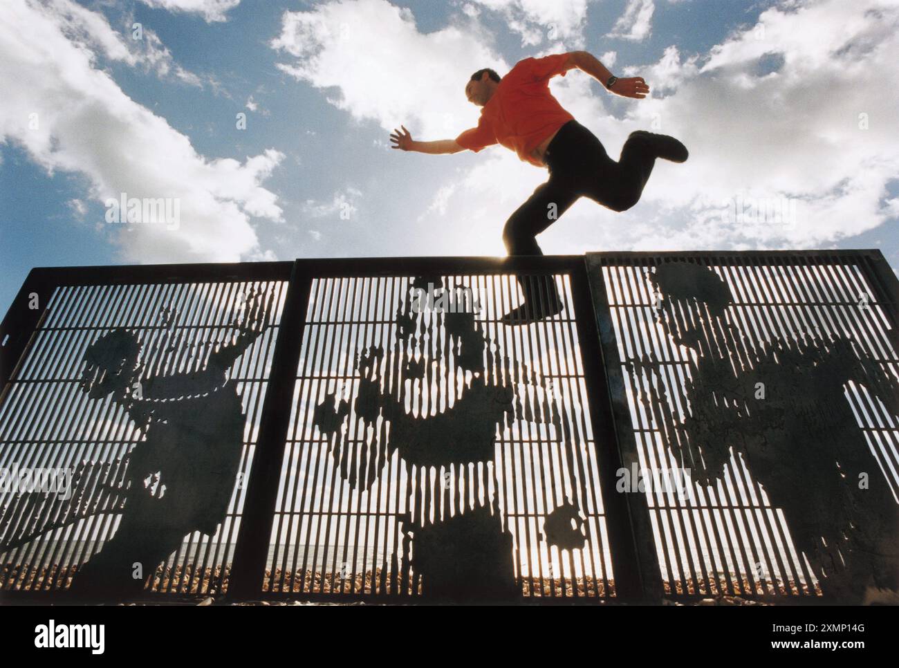 Sculptor bruce williams leaps over his laser cut panels of hi-res stock ...