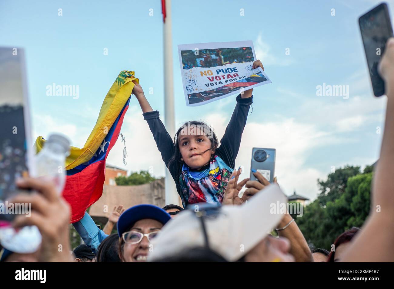 A Venezuelan kid holds a flag and a placard during a rally. Venezuelans ...