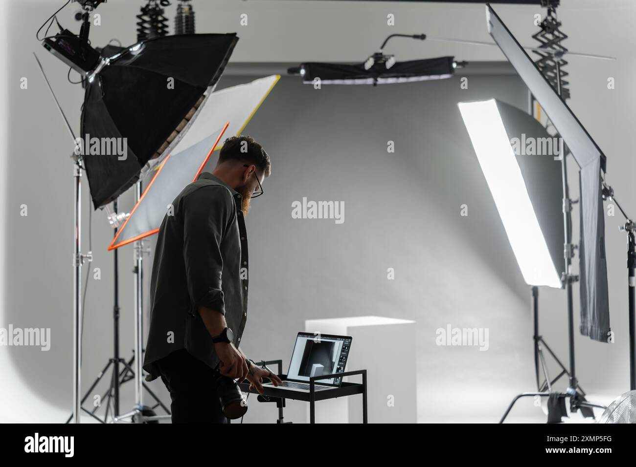 Photographer adjusting camera settings in professional studio with ...