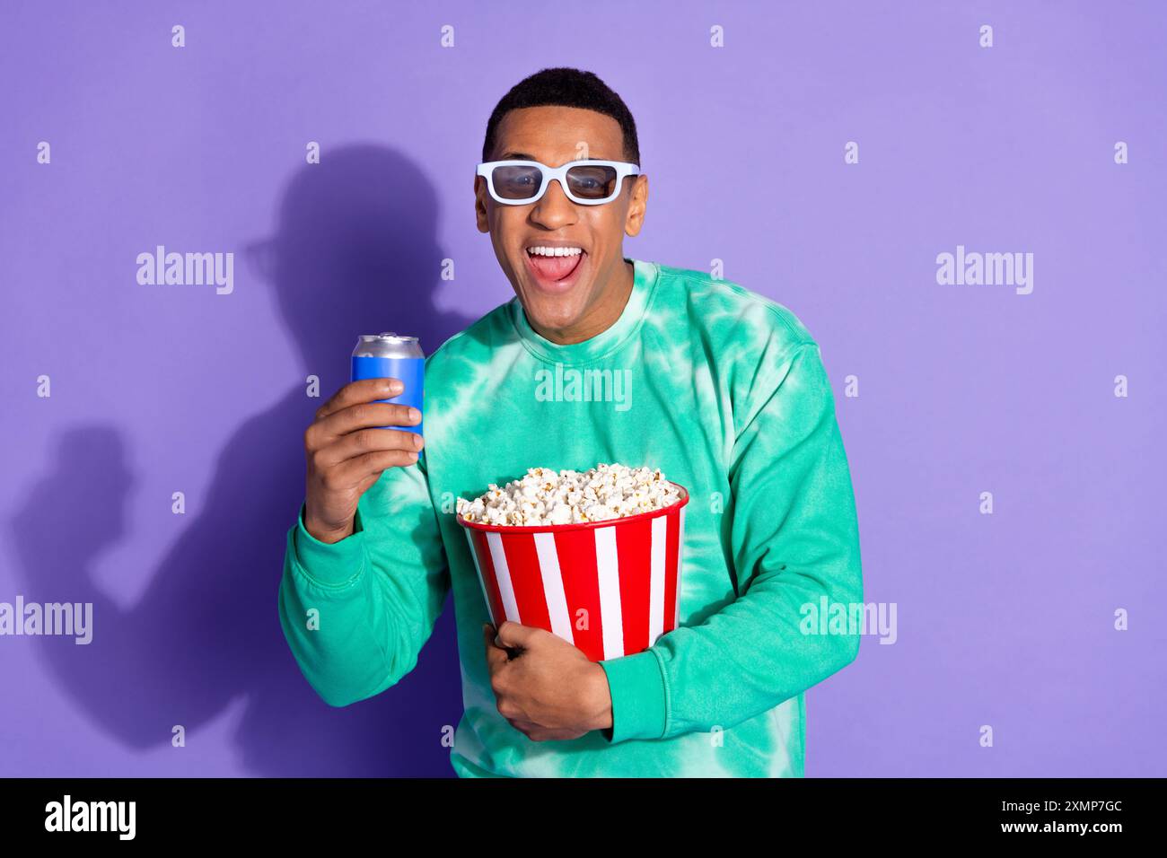 Photo of attractive funny guy wear teal sweatshirt enjoy film eat pop ...