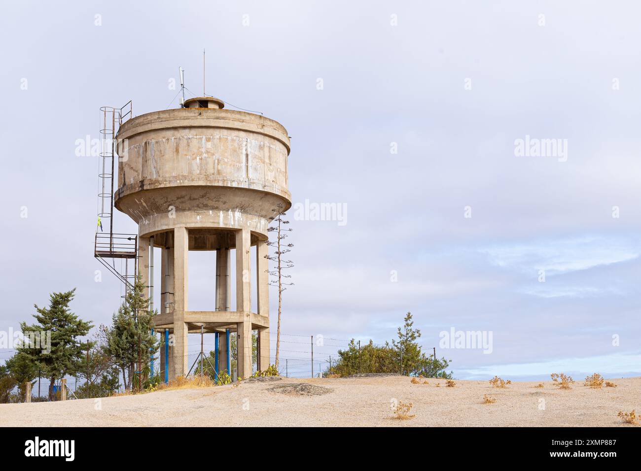 A concrete water tank in a rural landscape. It has access stairs ...