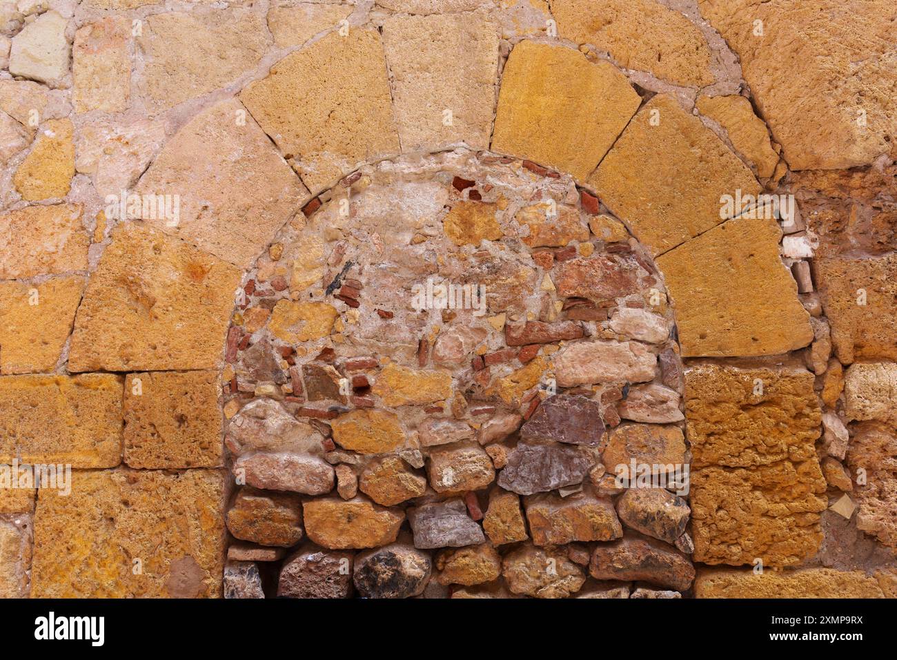 Rounded arch made of stones set in a textured wall Stock Photo - Alamy
