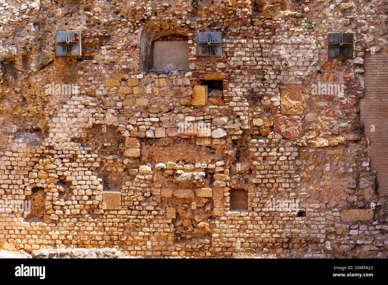 Textured wall fragment featuring various stone elements and openings ...