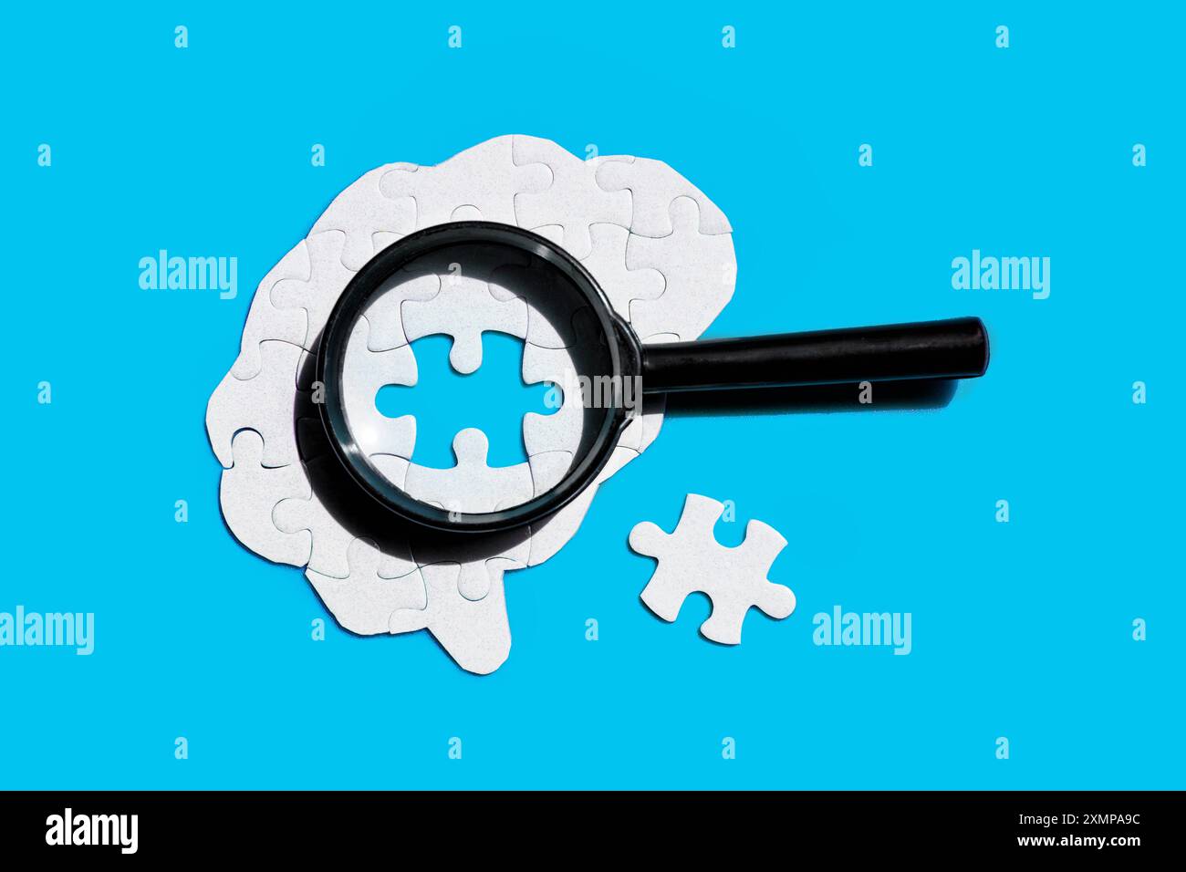 Magnifying glass placed on a human brain shaped puzzle with the final ...