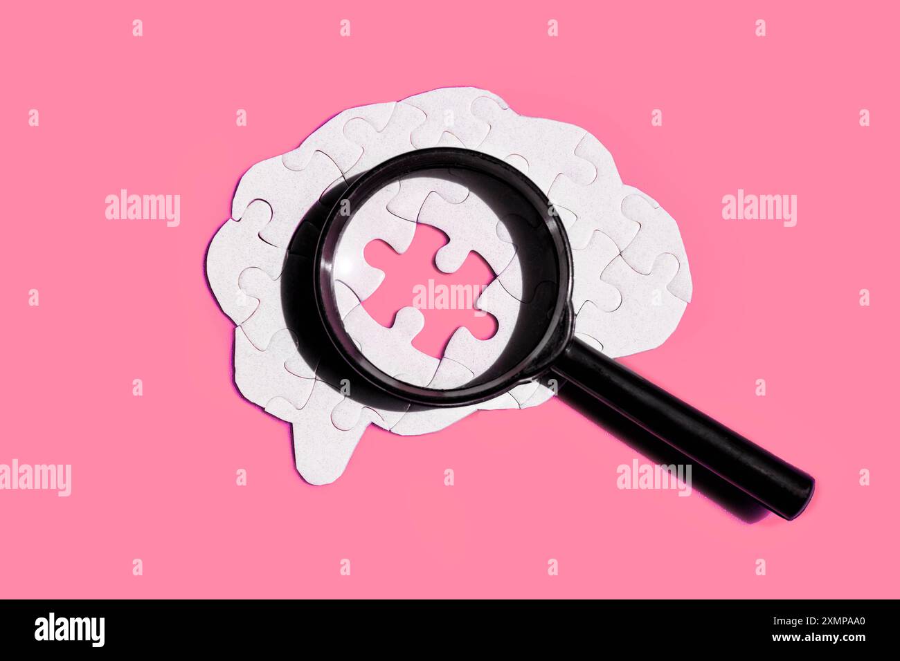 Flat human brain made of puzzle pieces placed under a magnifying glass ...