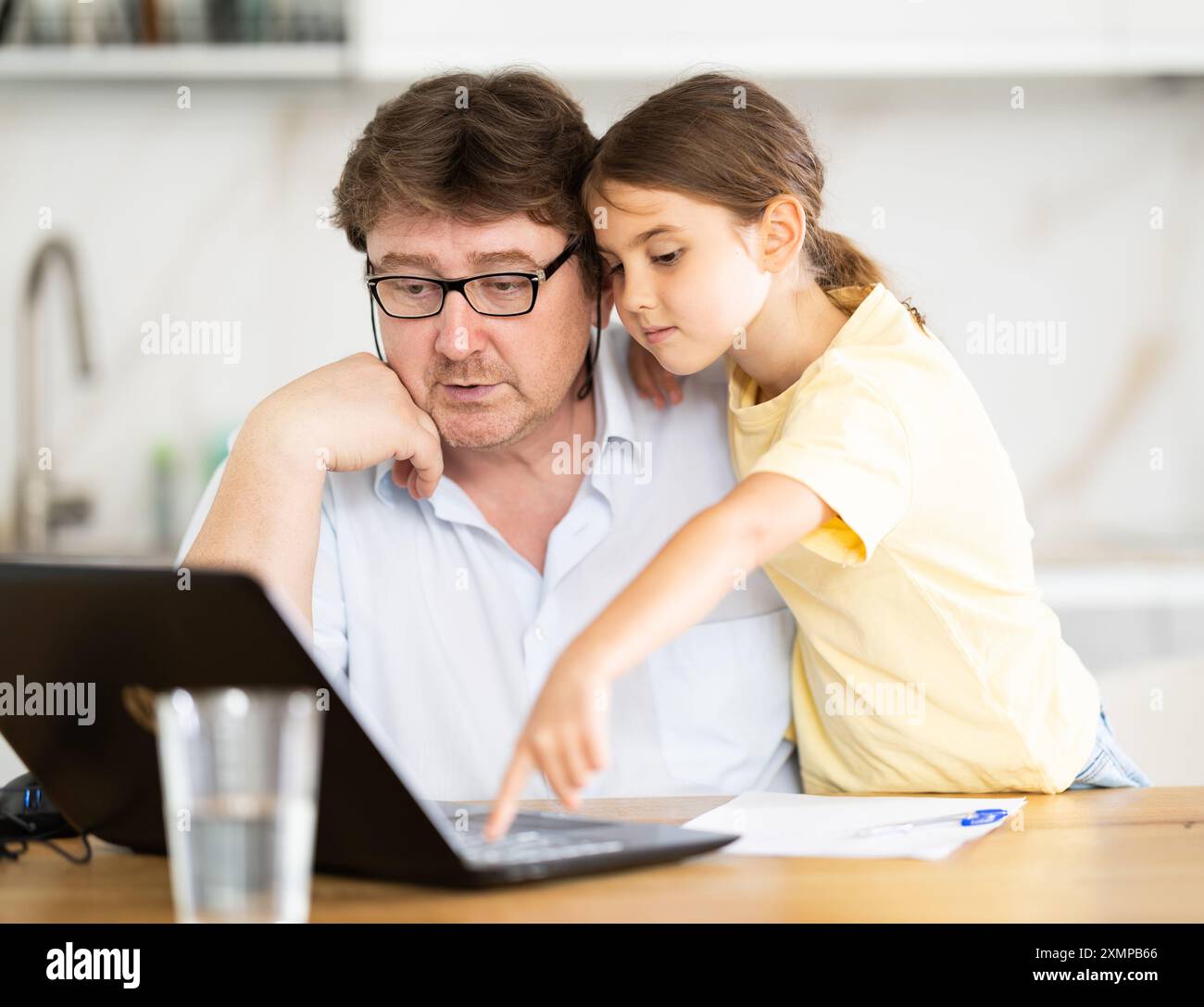 Father helps daughter do homework using laptop Stock Photo - Alamy