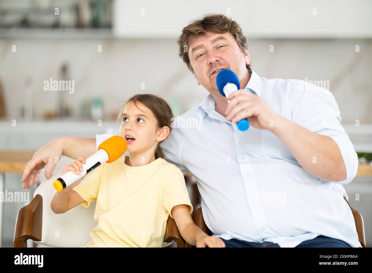 Karaoke time - father and daughter sing into microphones Stock Photo ...