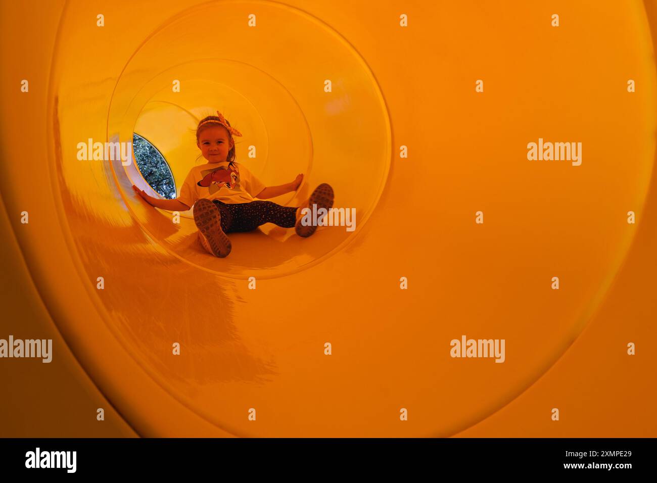 Little girl having fun in tube tunnel slide on playground Stock Photo ...