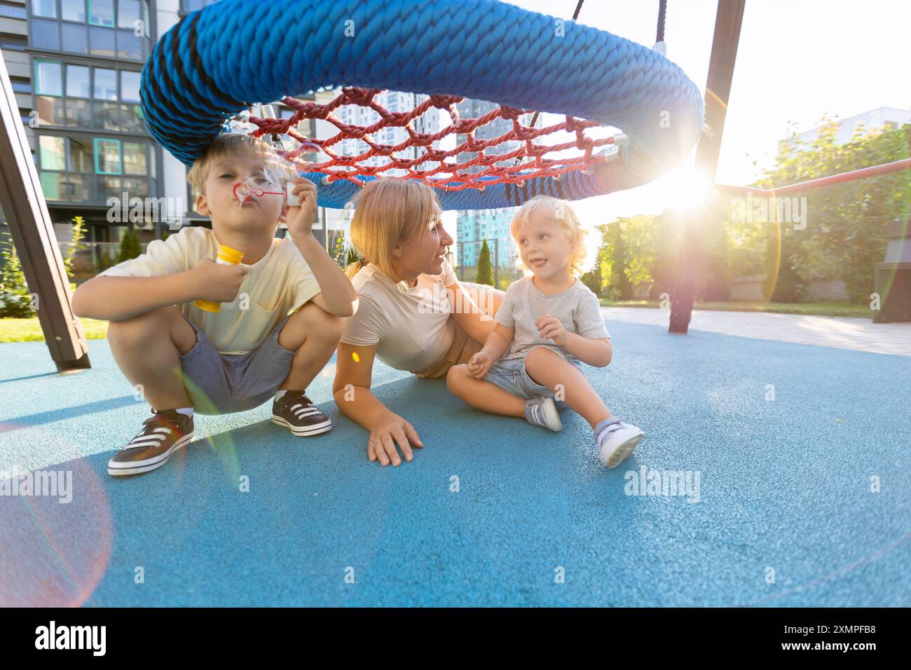 Mother Enjoys Fun Playtime With Two Sons on Vibrant Playground During ...