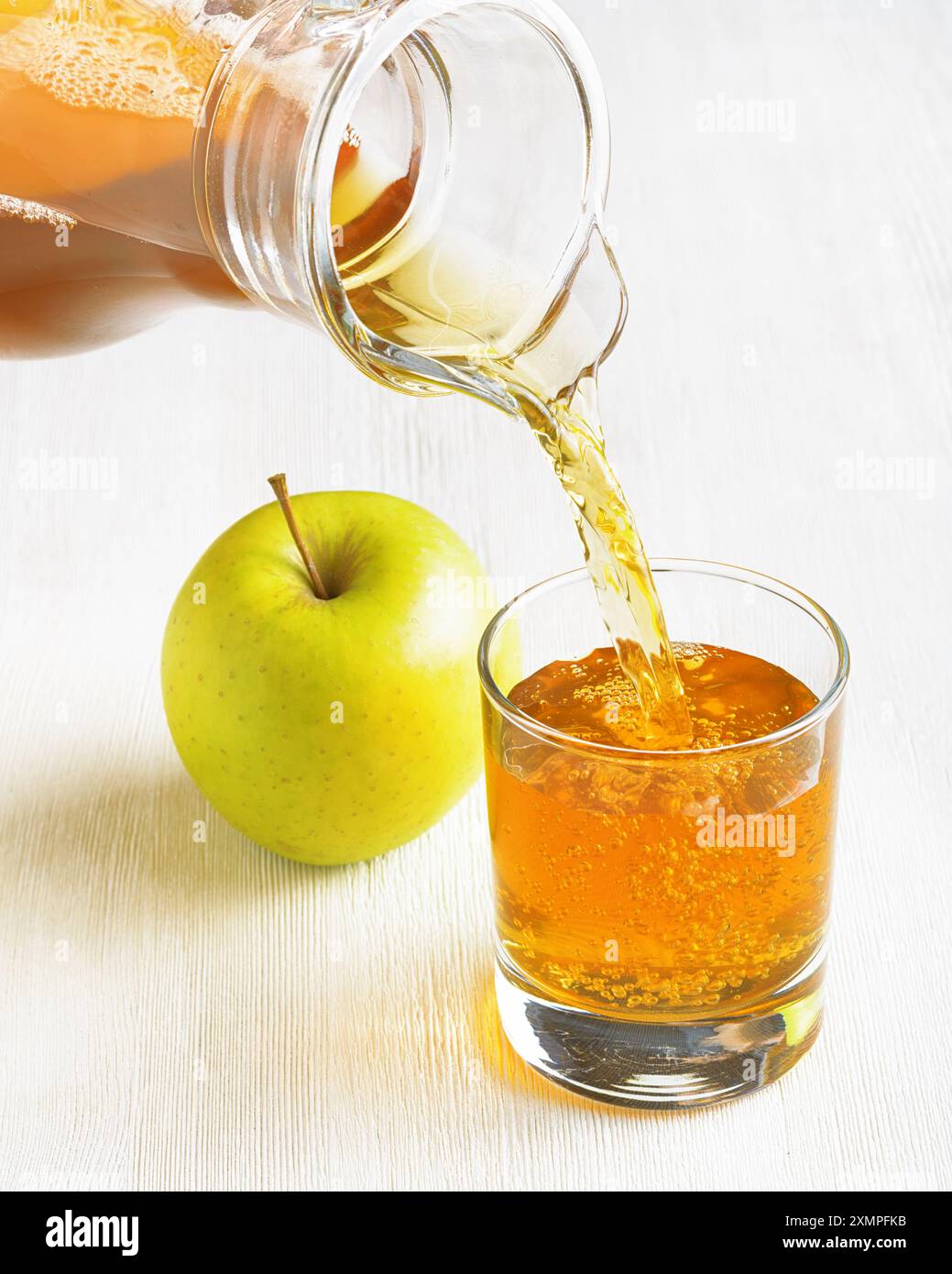 Apple juice pouring from jug into a glass Stock Photo - Alamy