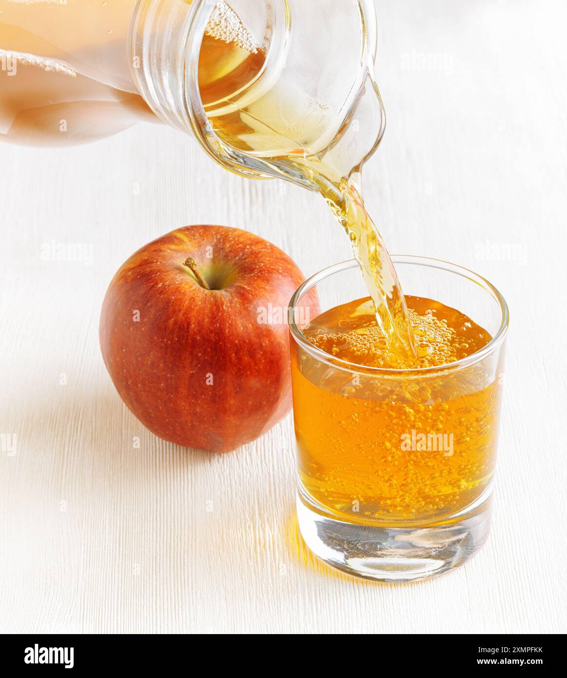 Apple juice pouring from jug into a glass Stock Photo - Alamy