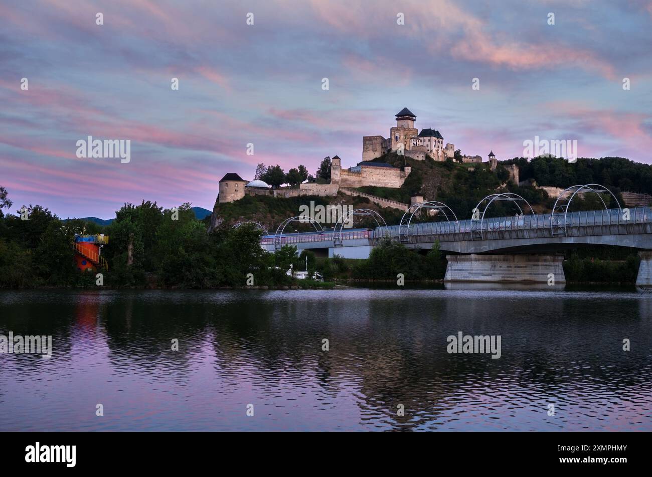 Summer landscape with river Vah, a modern railway bridge and a castle ...