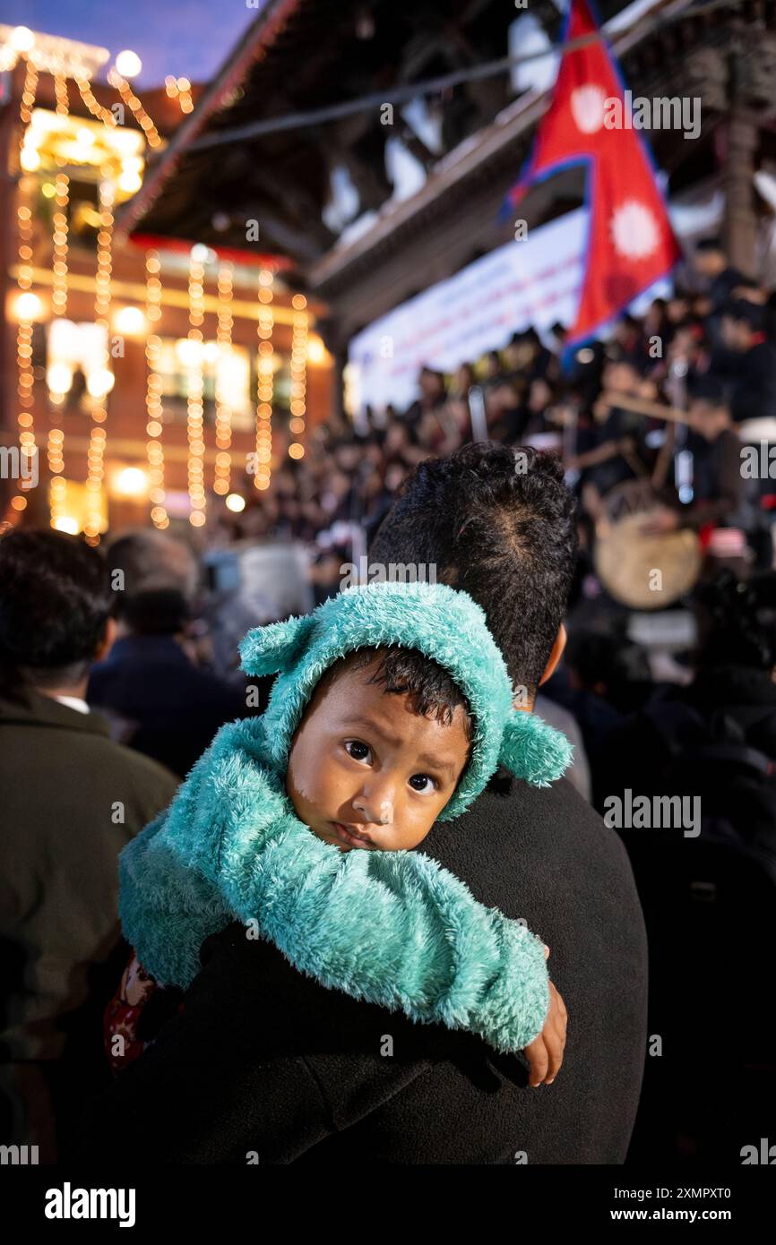 Young child cuddles in father's arms during evening Diwali festival of ...
