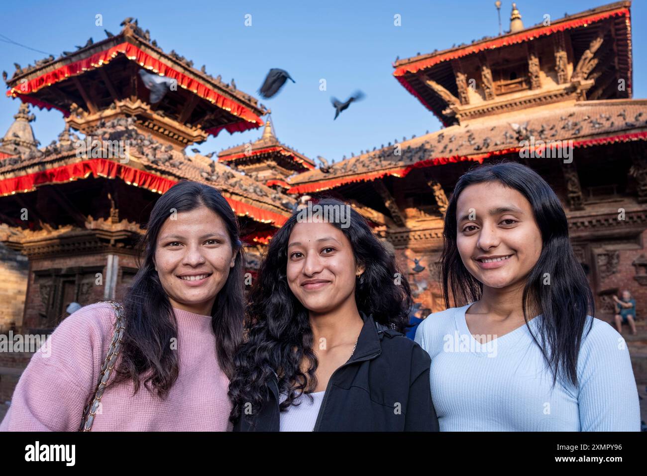 As ravens fly about young women friends pose for portrait in historic ...