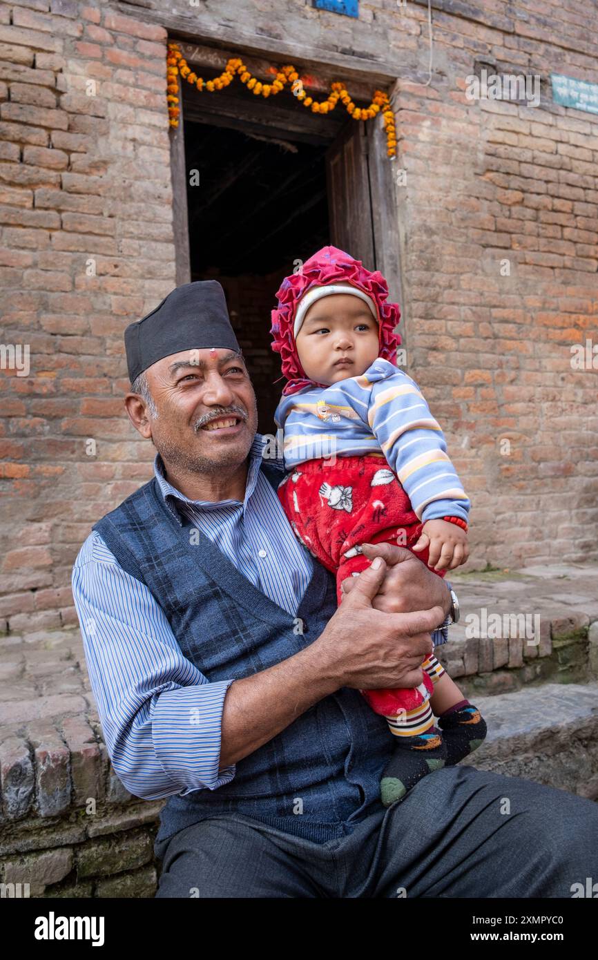 Nepalese grandfather with grand baby wears traditional bhadgaunle topi ...