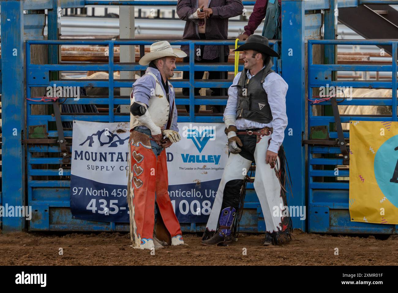 Two professional rodeo cowboys talking by the bucking chutes after ...