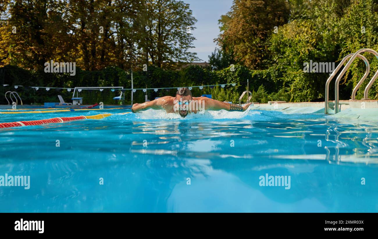 Wearing goggles, swimmer powers through water with butterfly stroke ...