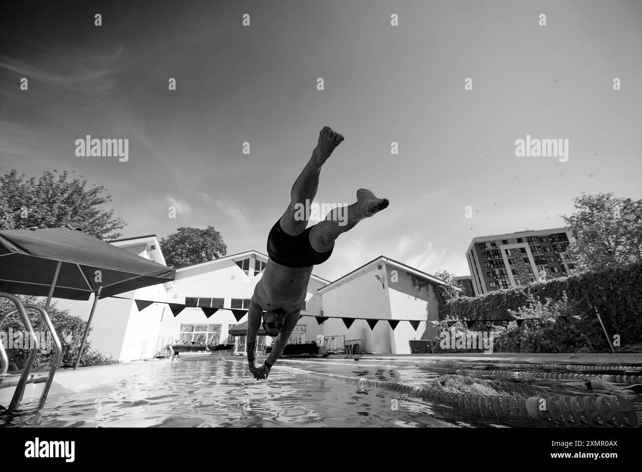 Black and white photo. Man, swimmer dives into pool outdoor with ...