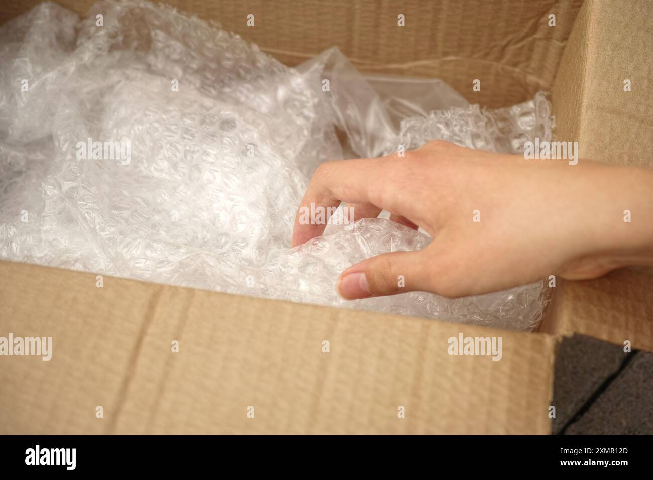 A person unboxing a cardboard box with bubble wrap inside of it. Close ...