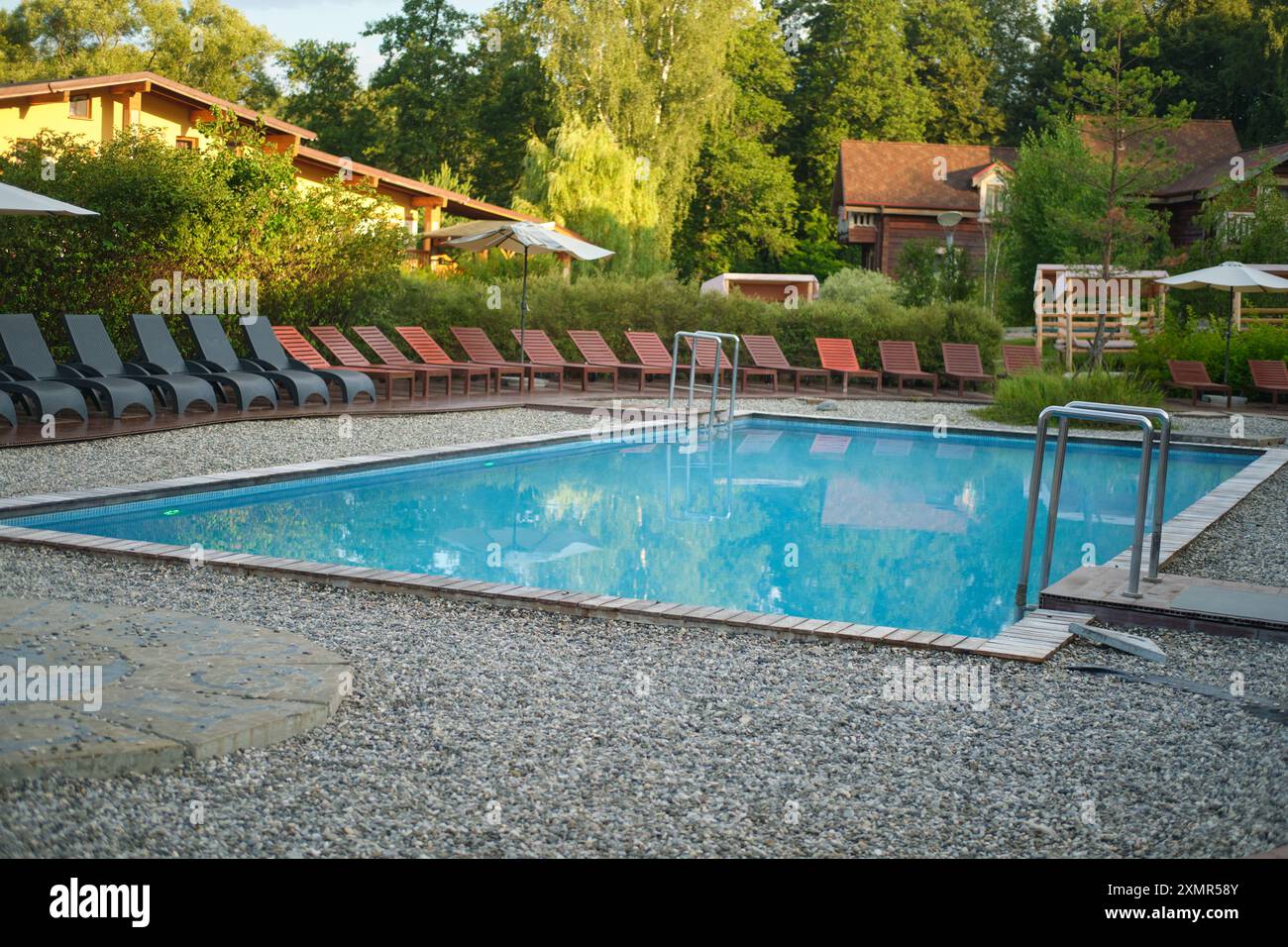 Outdoor swimming pool surrounded by lounge chairs and cottages, set in ...