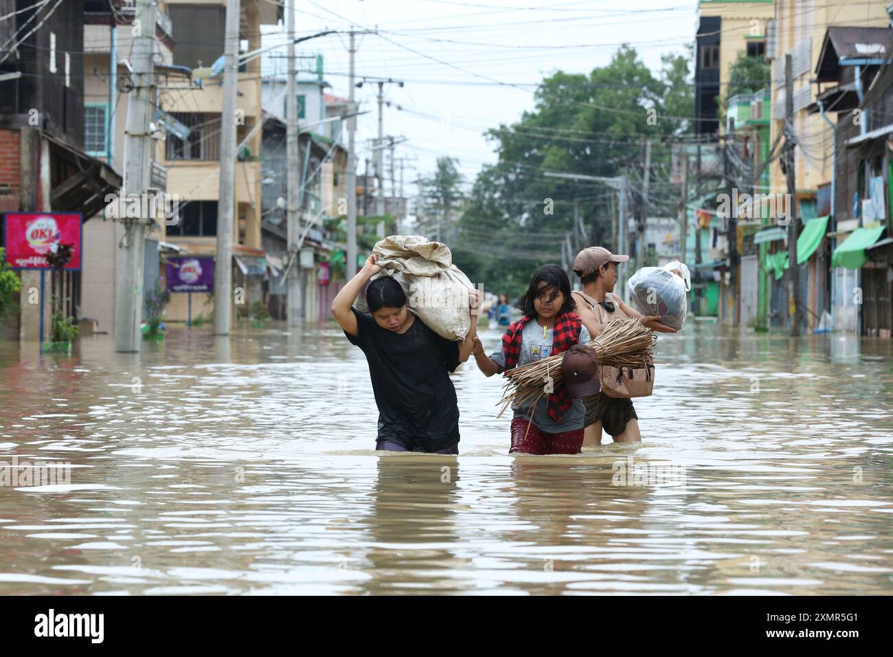 Bago. 29th July, 2024. People wade through a flooded area in Bago ...