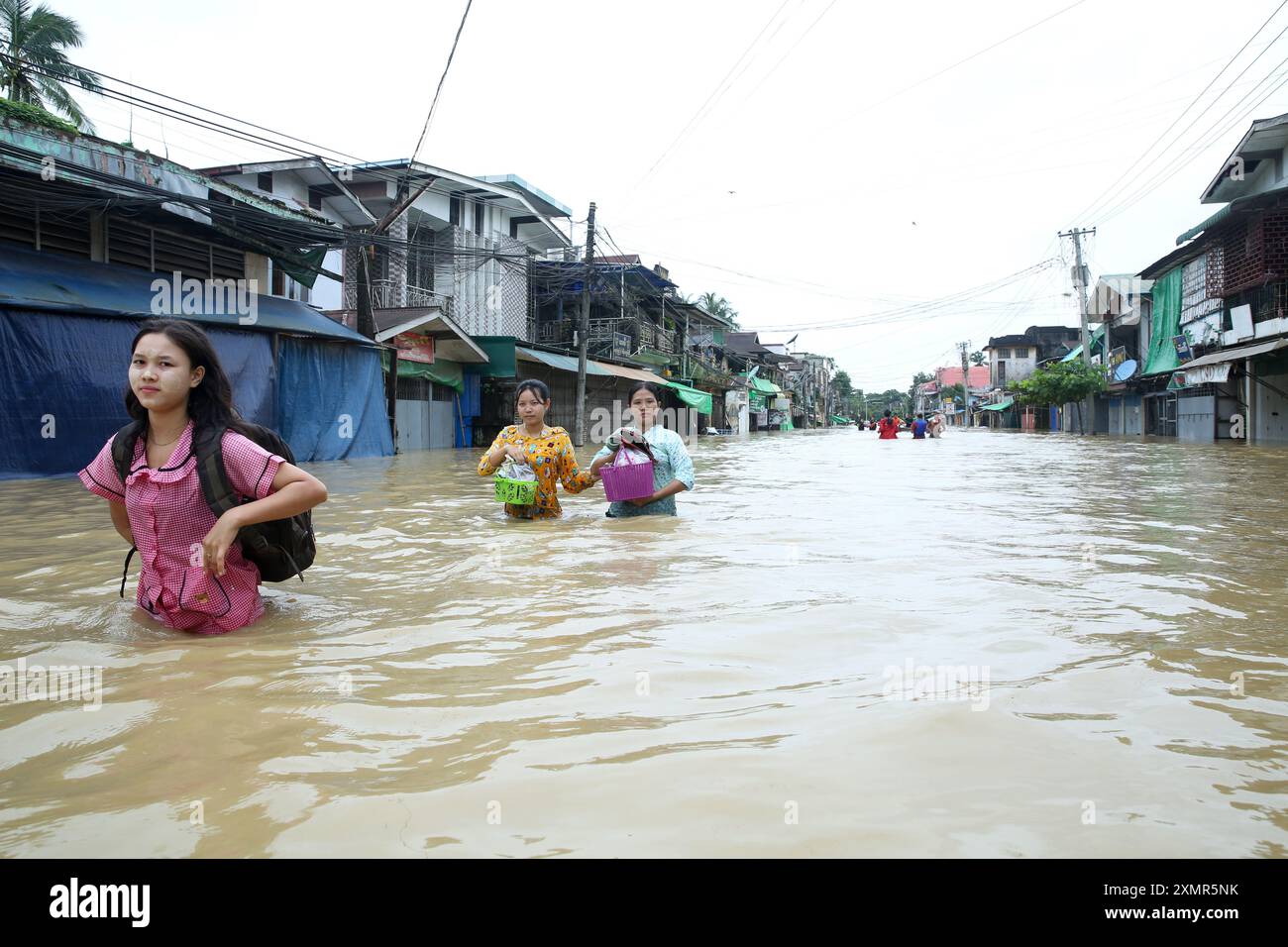 Bago. 29th July, 2024. People wade through a flooded area in Bago ...