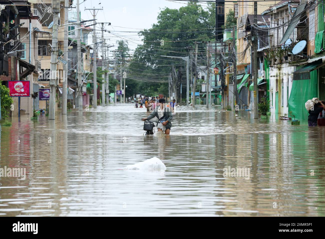 Bago. 29th July, 2024. People wade through a flooded area in Bago ...