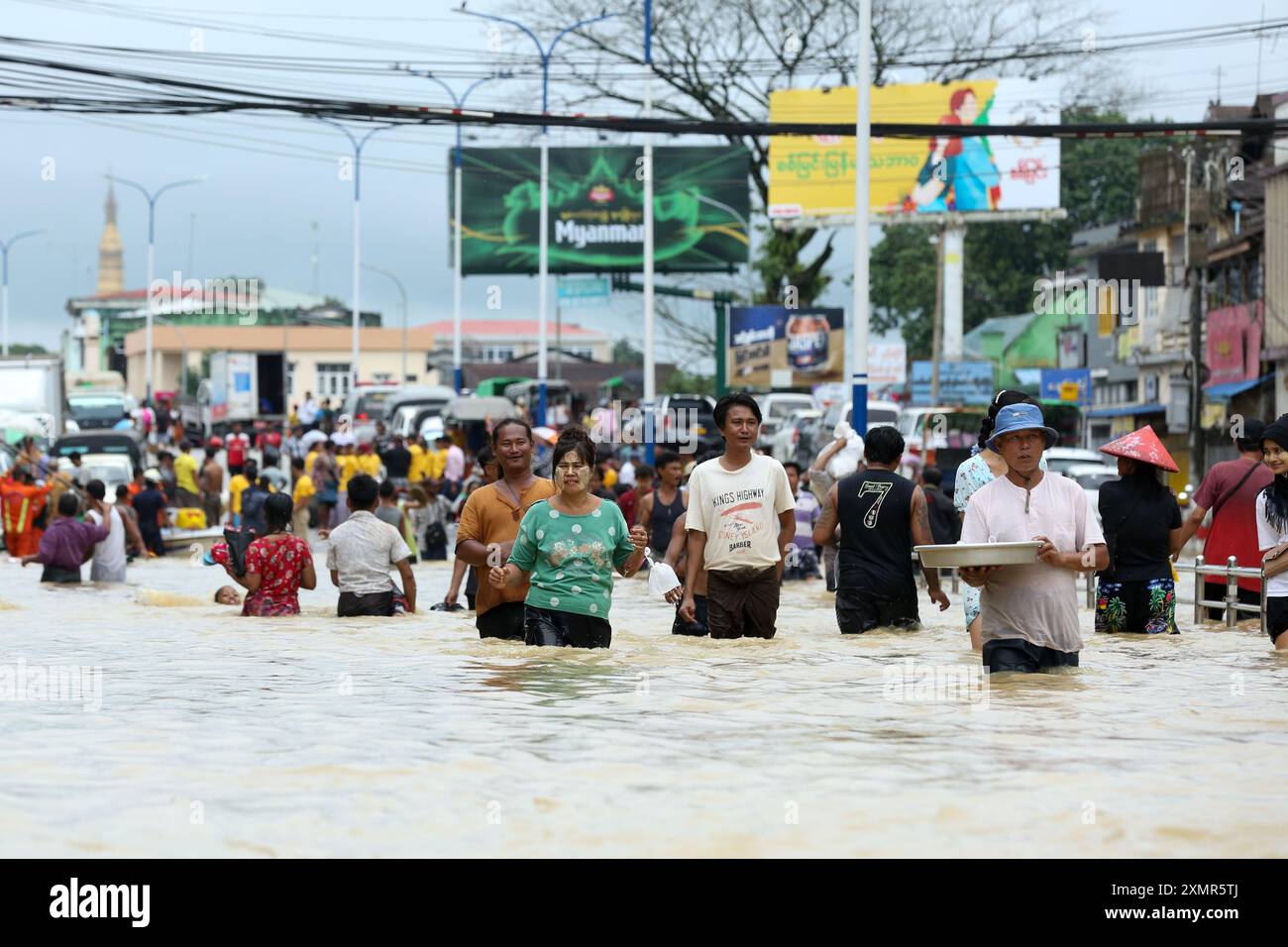 Bago. 29th July, 2024. People wade through a flooded area in Bago ...
