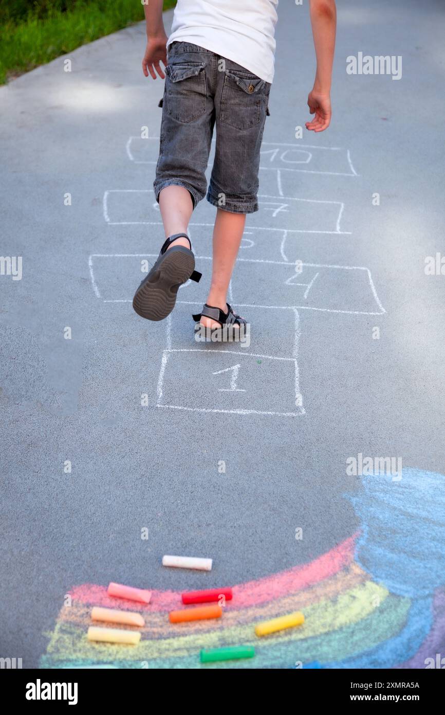 Hopscotch drawn with chalk on the pavement. Children's feet. Jumping on ...